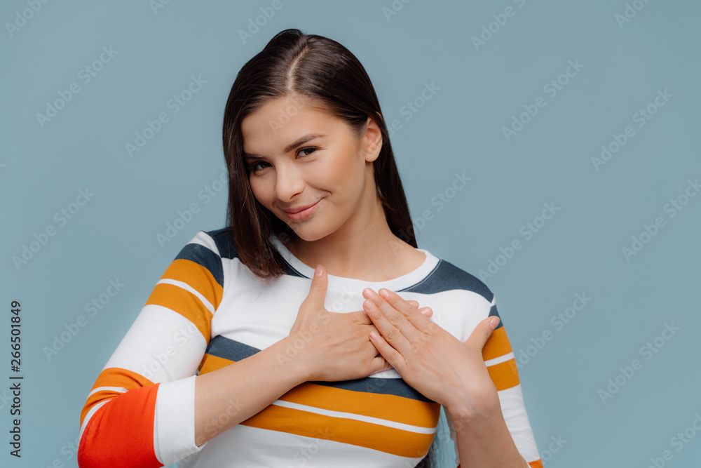 Friendly looking female keeps hands on chest near heart, expresses good ...