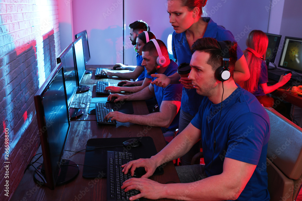 Young people playing video games on computers indoors. Esports ...
