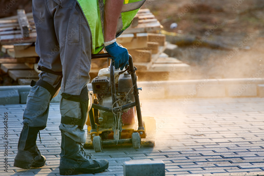 Foto de Stock Worker in uniform and knee pads use vibratory plate ...