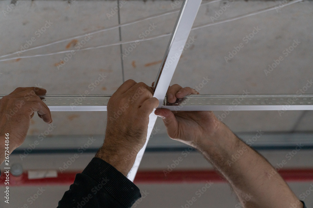 Construction worker assemble a suspended ceiling fixing metal frame ...