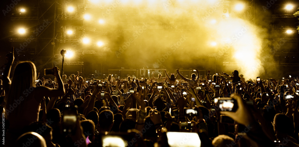 Back view of audience using mobile phones in front of stage and music ...