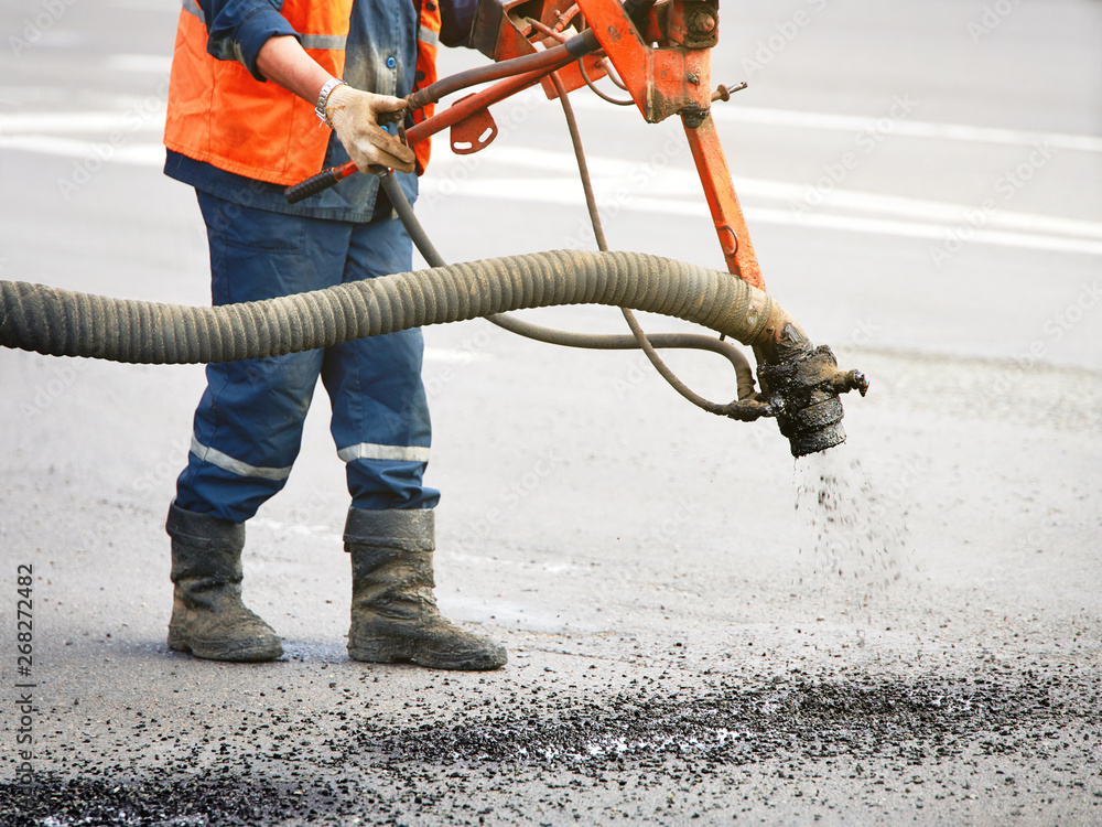 Professional worker in uniform during fast repair road surface ...
