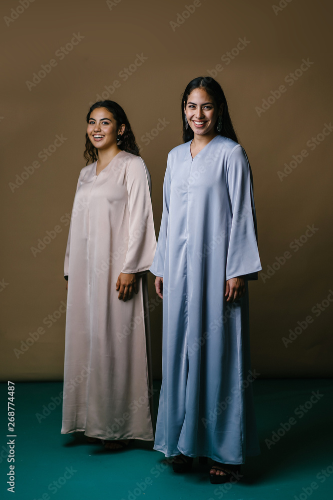 Portrait of two young Middle Eastern Muslim women smiling as they pose ...