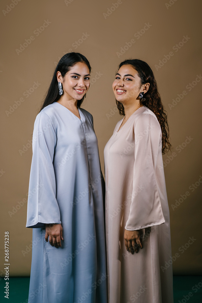 Portrait of two young Middle Eastern Muslim women smiling as they pose ...