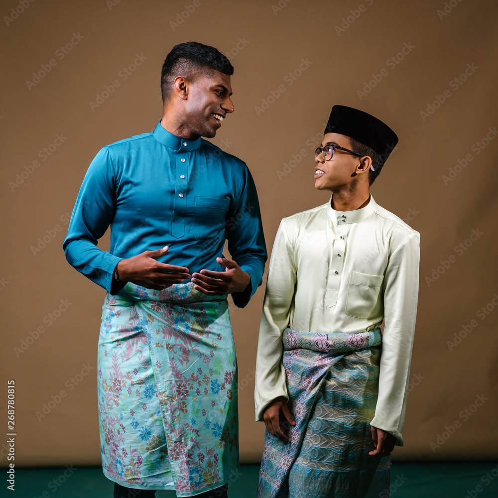 Foto A young Malay and Indian men smile and laugh as they stand next to ...