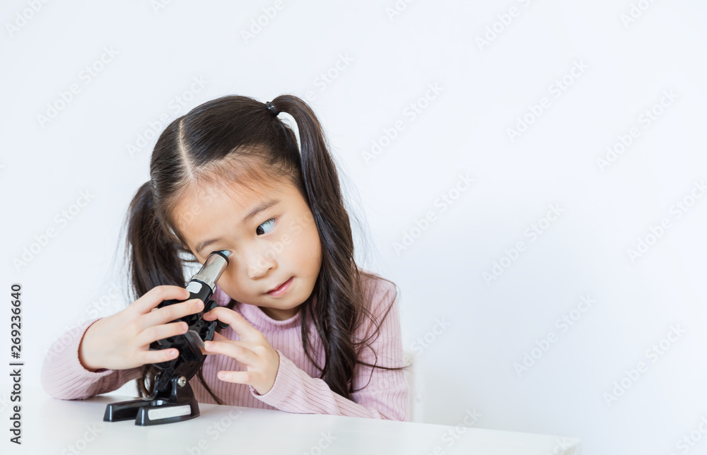 Beautiful asian little girl looking at a microscope in a classroom ...