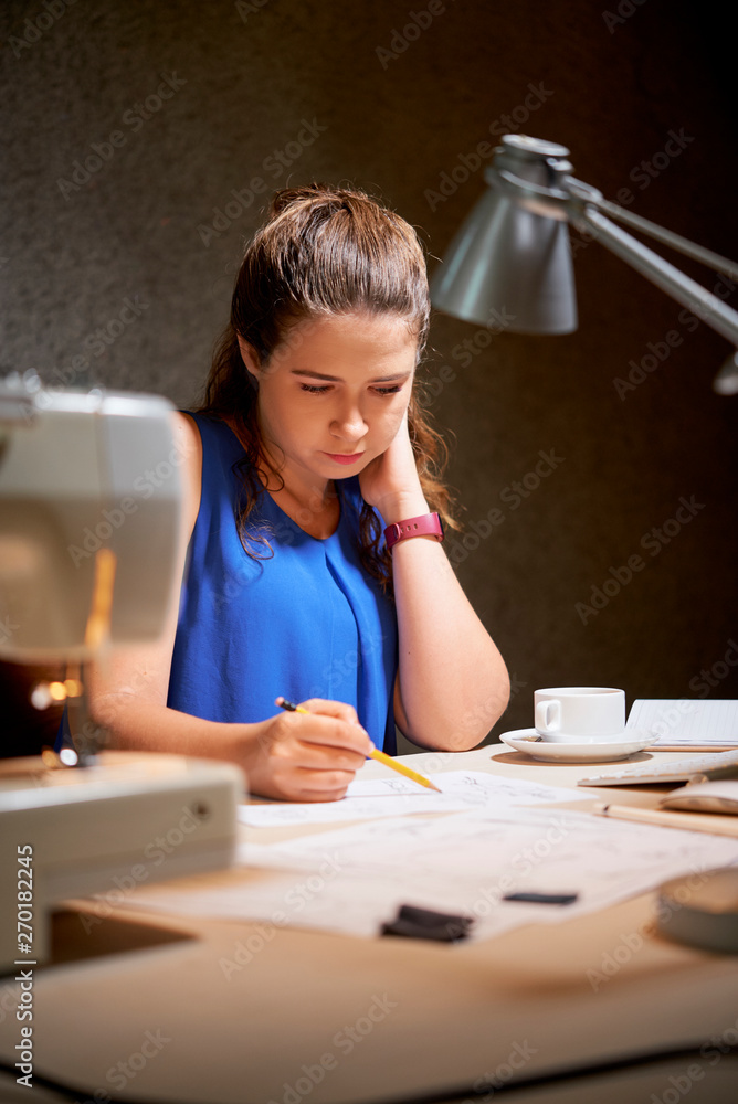 Young serious woman sitting at her workplace and concentrating on her ...