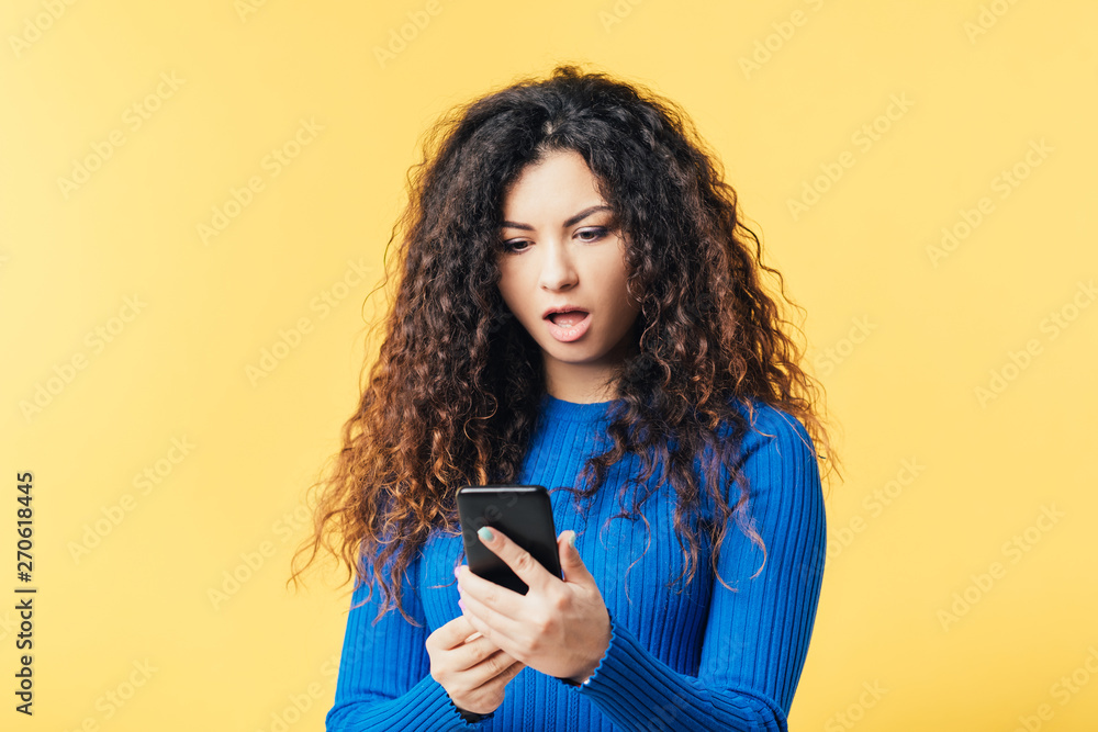 Beautiful young woman looking at smartphone. Mouth wide open shocked ...