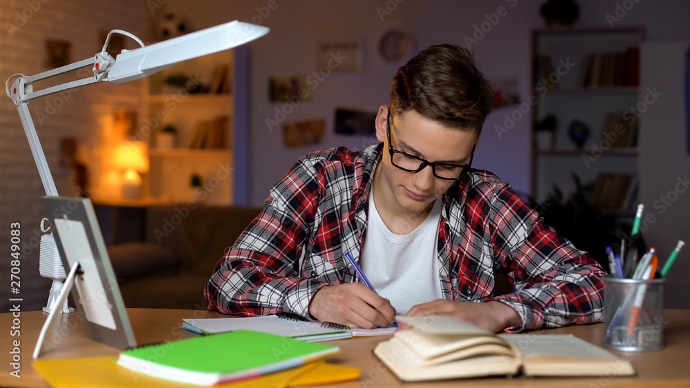 Diligent student doing his hometask at campus, working on diploma ...