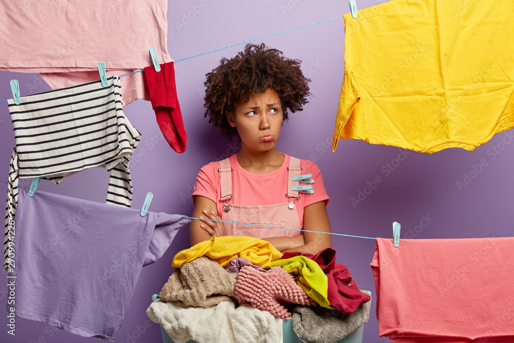 Offended miserable African American woman looks aside, purses lips, crossed hands, doesnt want ...