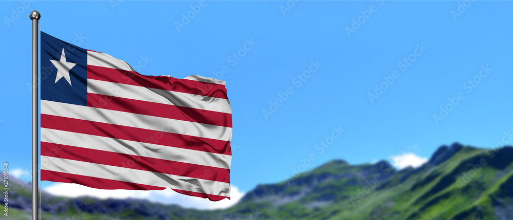 Liberia flag waving in the blue sky with green fields at mountain peak ...
