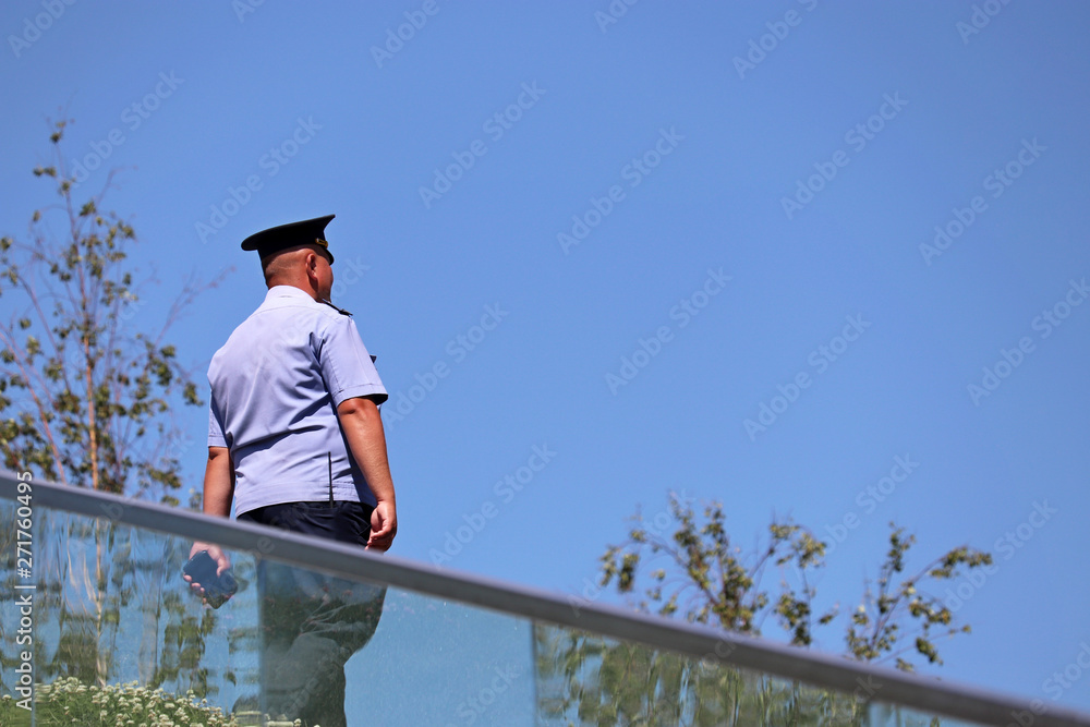 Policeman patrolling a summer park. Police officer walking on a blue ...