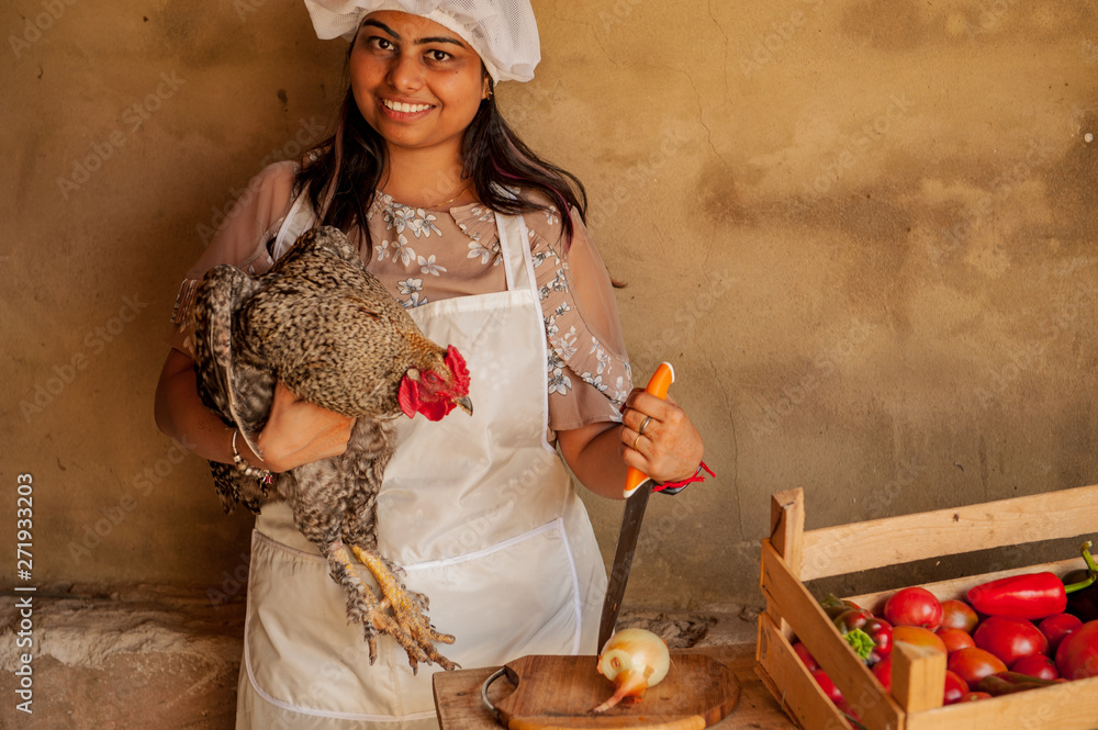 Attractive Indian woman cook posing in kitchen with chicken in her ...