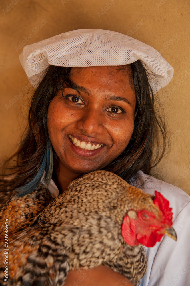 Attractive Indian woman cook posing in kitchen with chicken in her ...