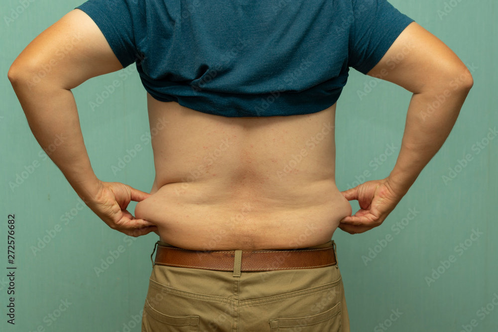 full man holds his hand folds of fat on their sides, view from behind ...