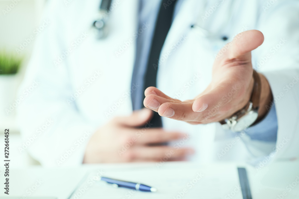 Male doctor making welcome gesture, politely inviting patient to sit ...