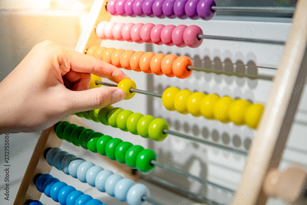 Male hand calculating with beads on wooden rainbow abacus for number ...