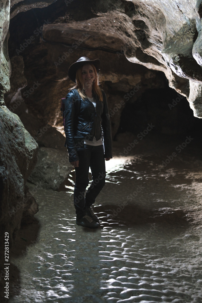 Girl exploring huge cave. Adventure traveller dressed cowboy hat and ...