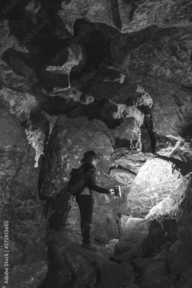 Girl exploring huge cave. Adventure traveller dressed cowboy hat and ...