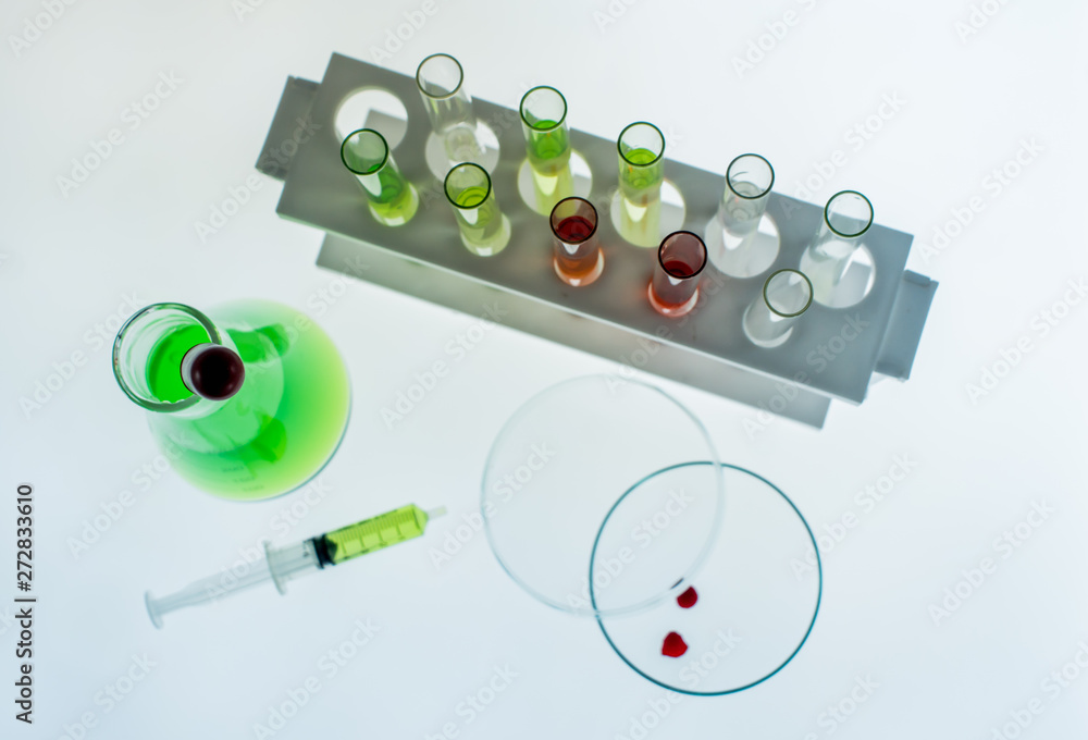 Erlenmeyer flask, Petri dish, Test tubes and a syringe with drops of ...