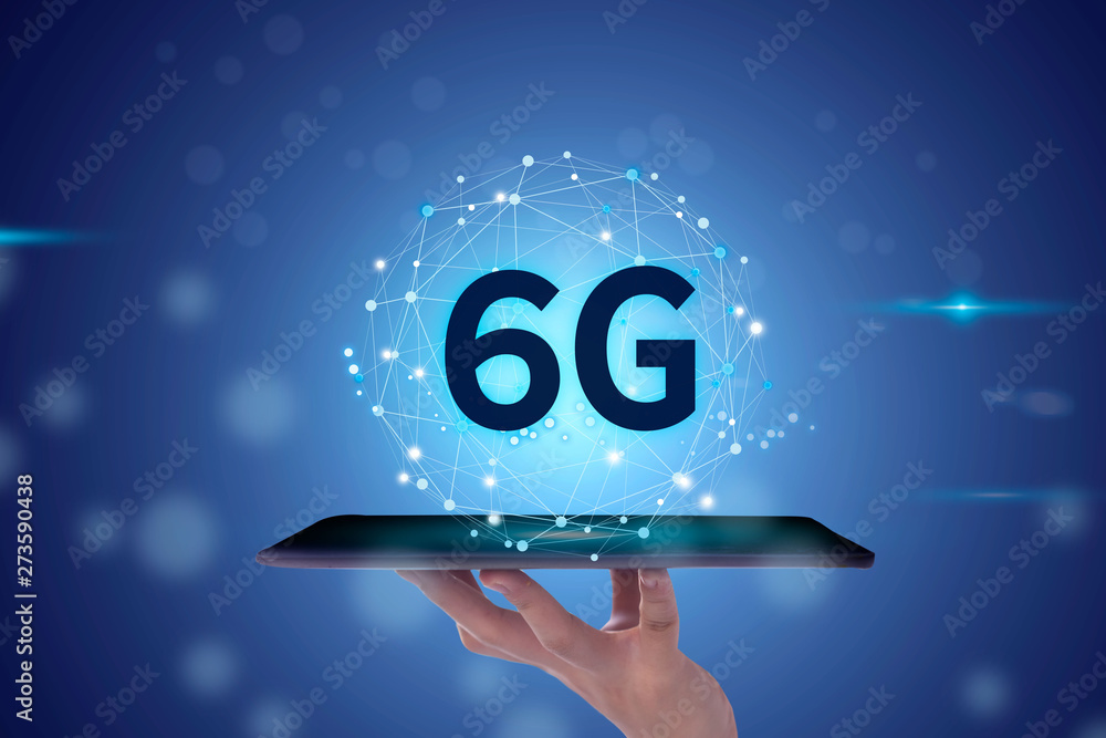 Hand holding a mobile phone with “6G" text on virtual screen ...