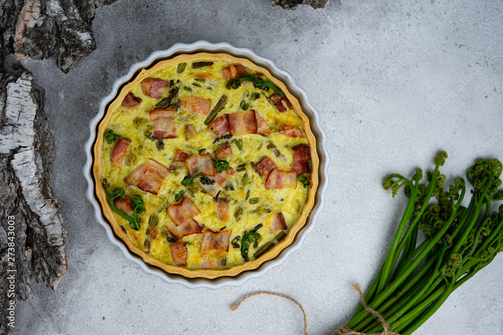 Baked Lauren quiche with bacon and young bracken shoots on white ...