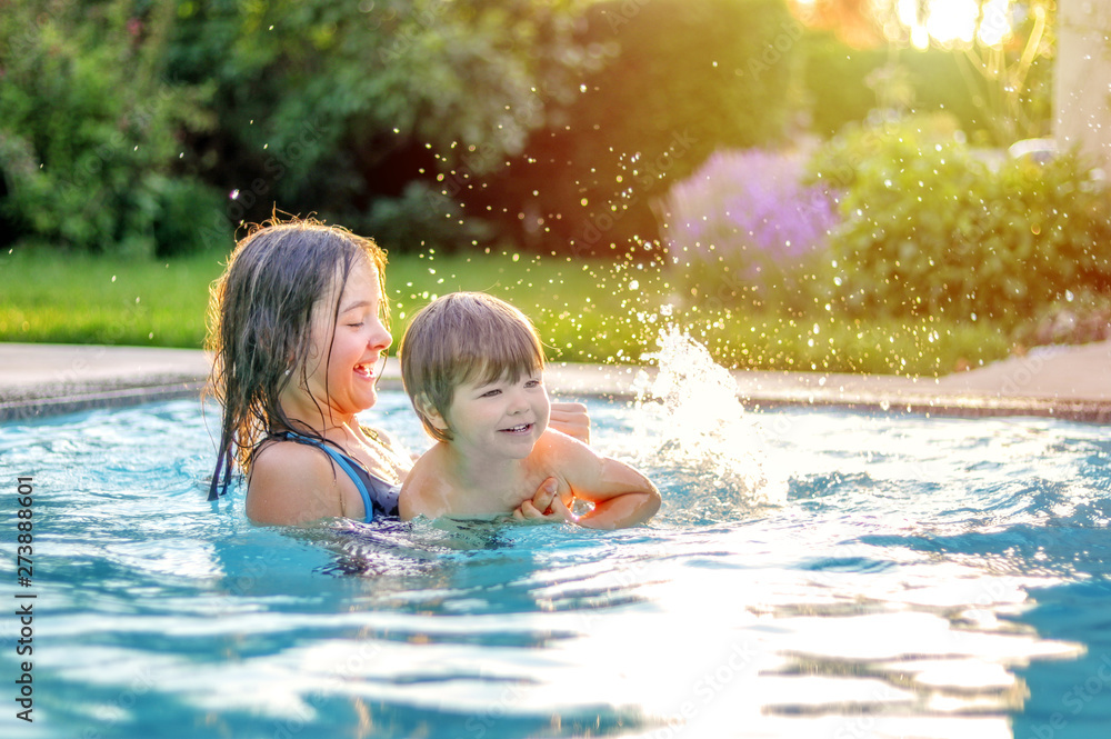 Happy siblings playing in swimming pool outdoors in garden. Preteen ...