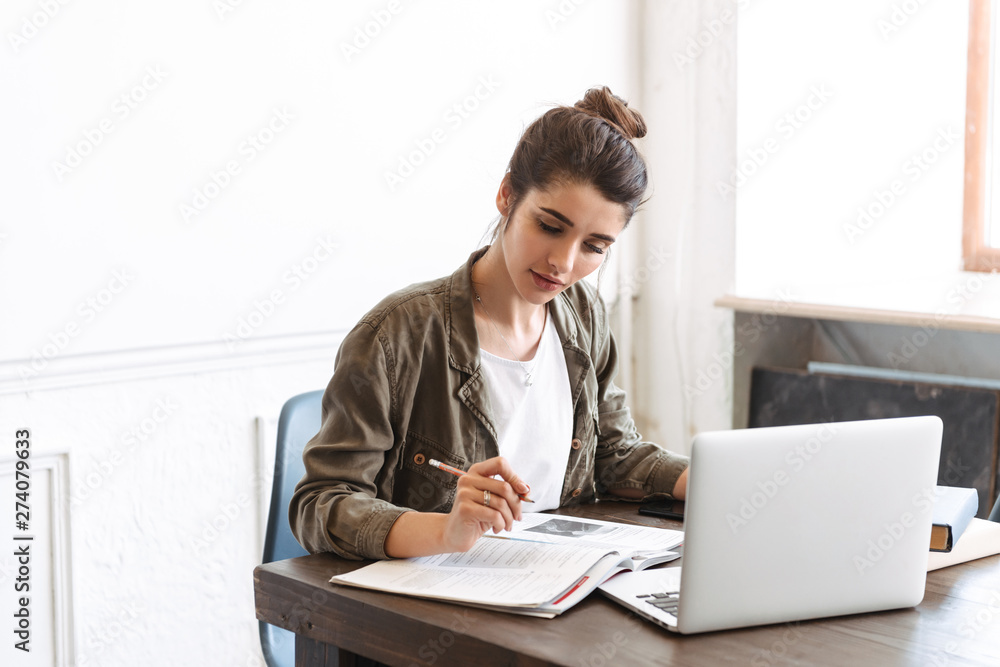 Beautiful young concentrated woman using laptop computer indoors ...