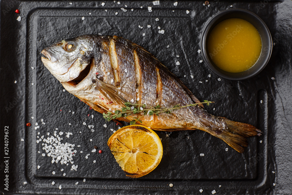 Delicious grilled dorado or sea bream fish with lemon slices, spices ...