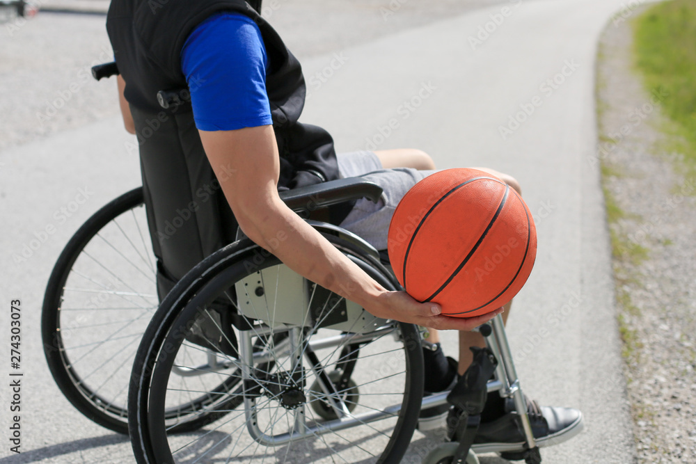 Disabled young basketball player on a wheelchair holding ball and ...