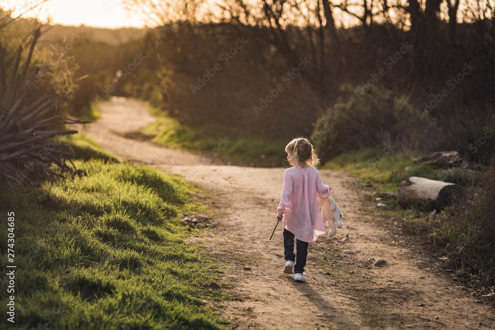 Foto de Stock Little girl walking away on trail with her stuffed animal ...