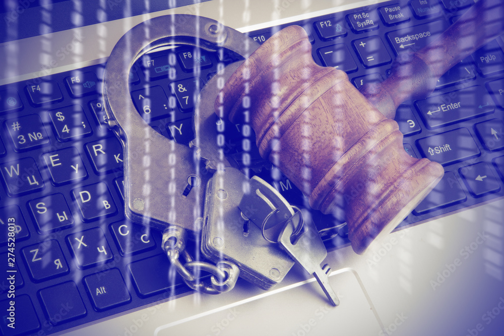 Cyber law and crime concept, handcuffs with keys and judge gavel on laptop with binary code ...