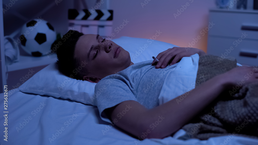 Nicotine addicted teen boy falling asleep with cigarette in bed risk of ...