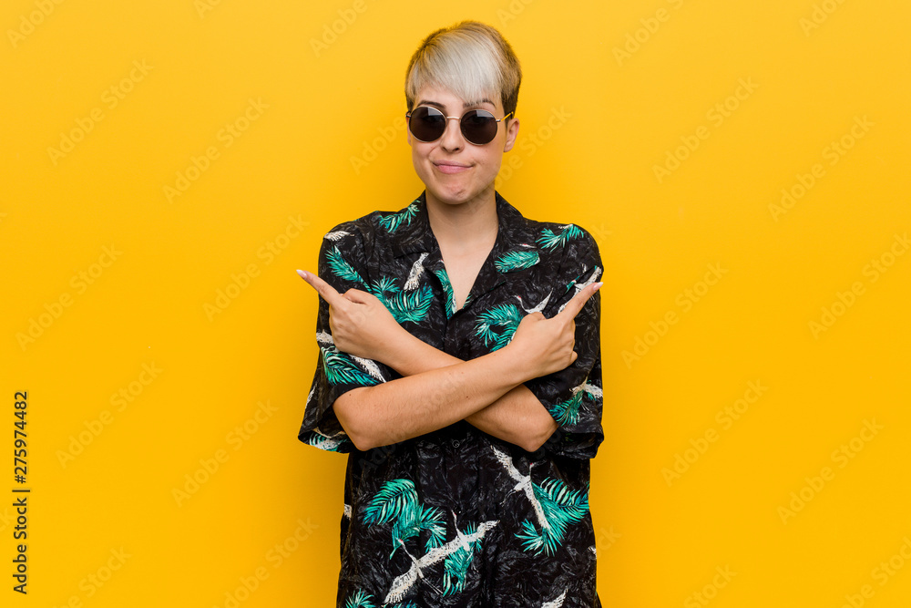 Young curvy woman wearing a summer look points sideways, is trying to choose between two options ...