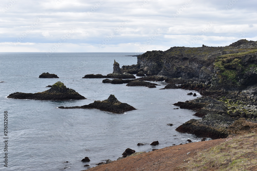 Hiking trail from Anarstapi to Hellnar with the raw ocean und big rocks and mountains in the ...