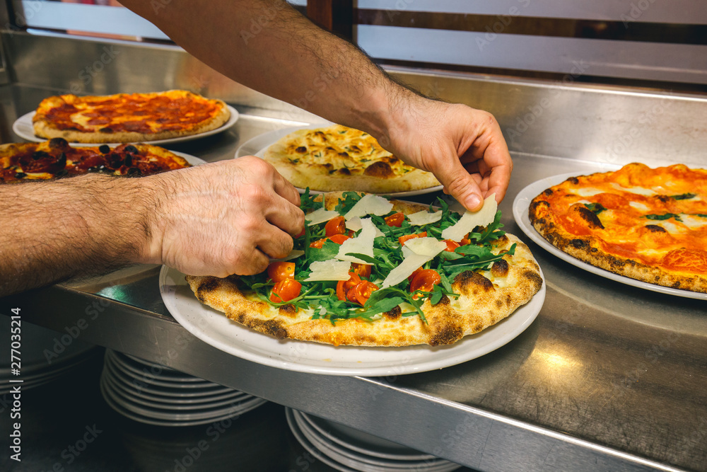 Preparing italian pizza with Parmigiano cheese tomato garnished with ...
