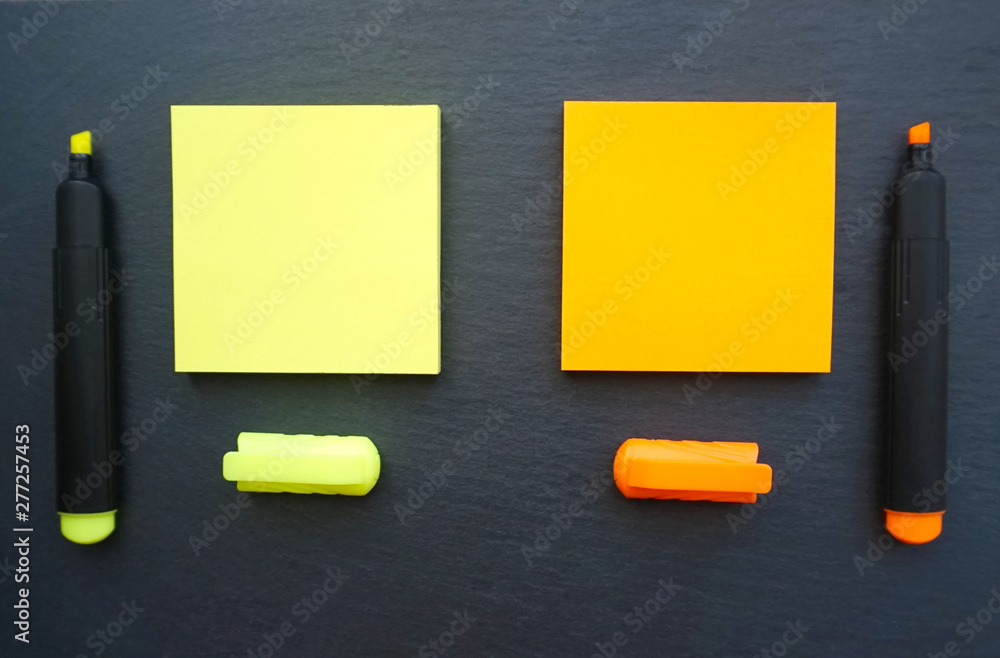 Sticky notes in yellow and orange color with marker pens in the same ...