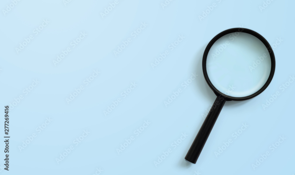 Magnifying glass on blue colour background with copy space. Searching ...