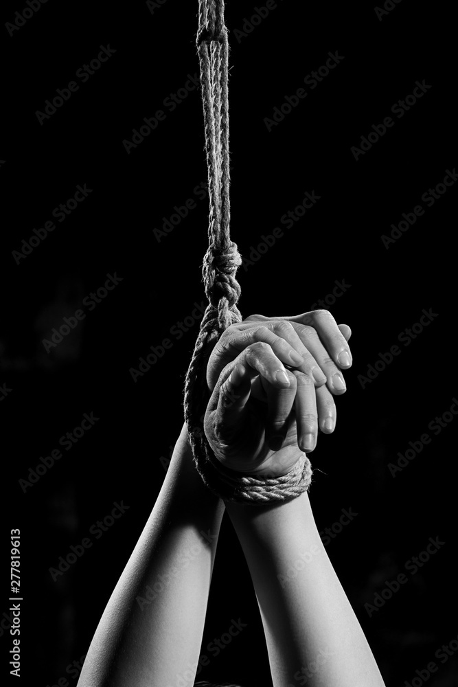 Hands of a victim tied up with rope hanging on ceiling Stock Photo ...