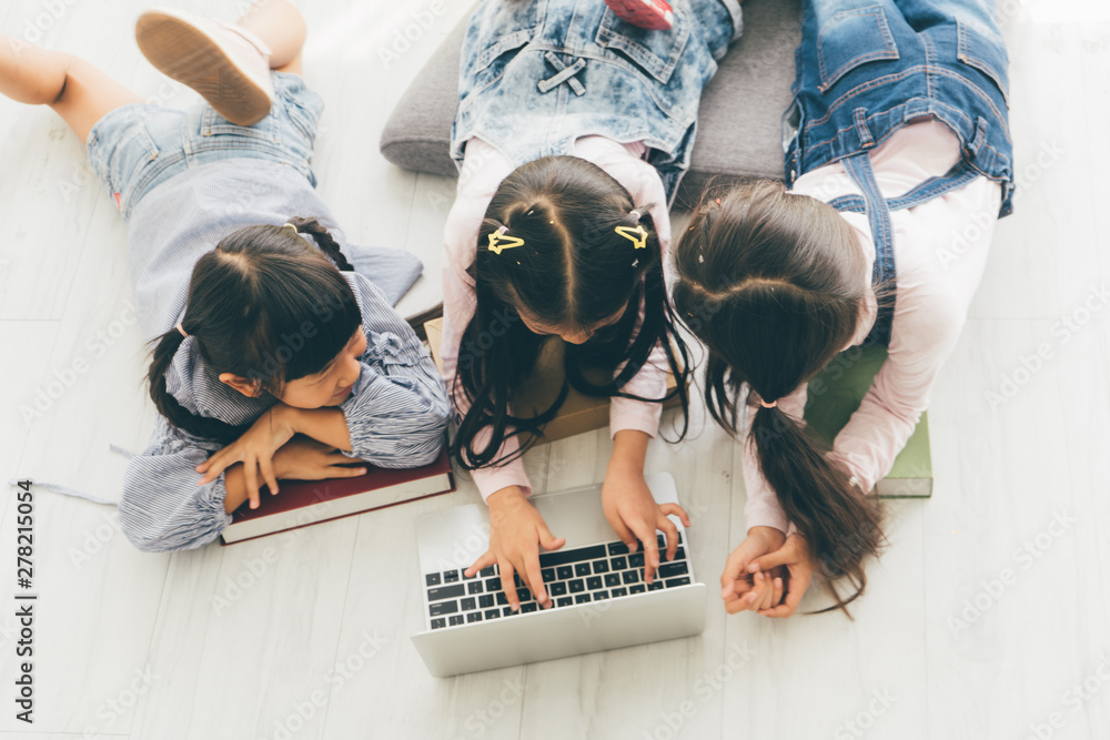 Three aisan children, Three sister, lay on the floor and use a laptop ...