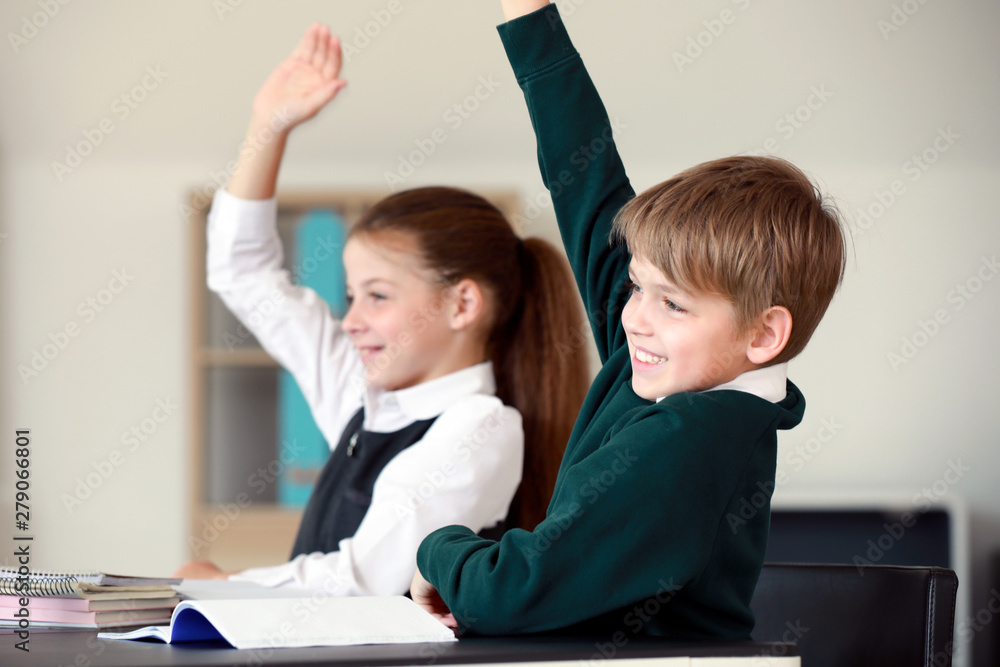 Cute little children raising hands during lesson in classroom Stock ...