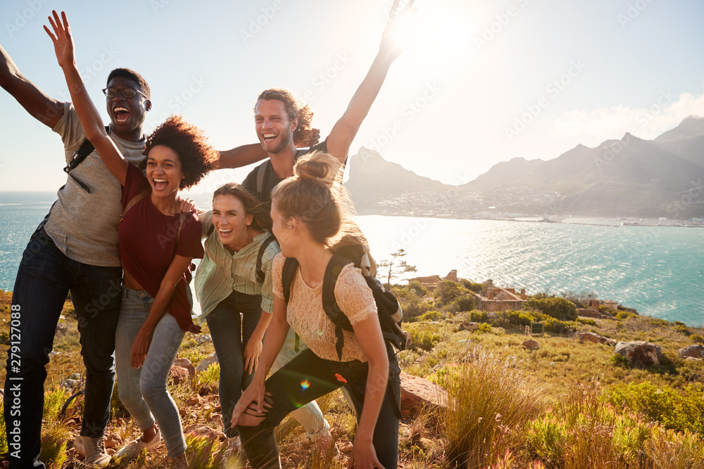 Millennial friends on a hiking trip celebrate reaching the summit and ...