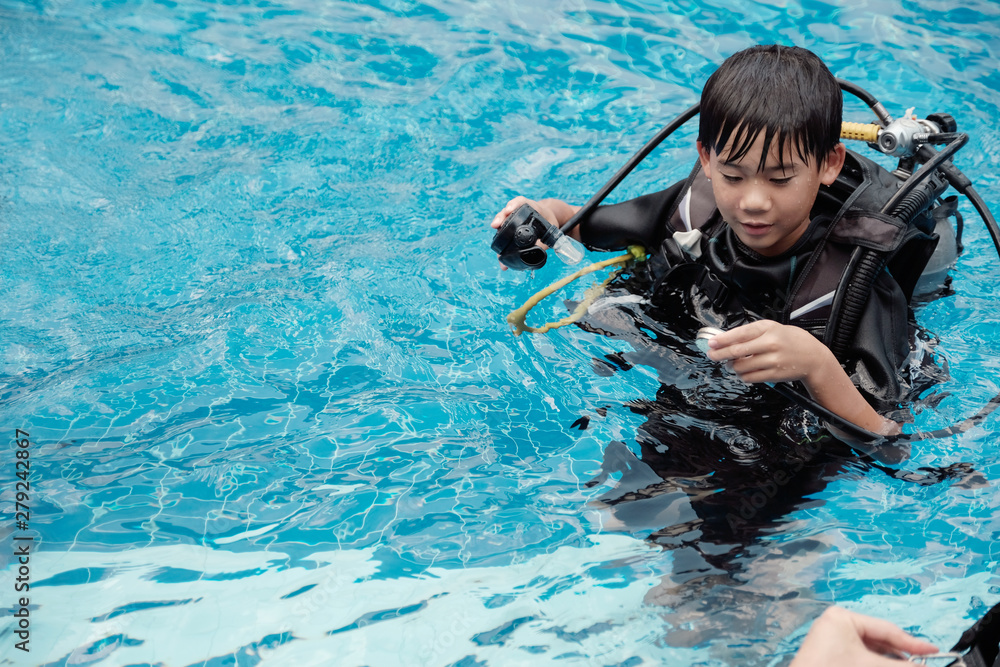 Young little Asian boy scuba diver checking pressure gauge and holding ...