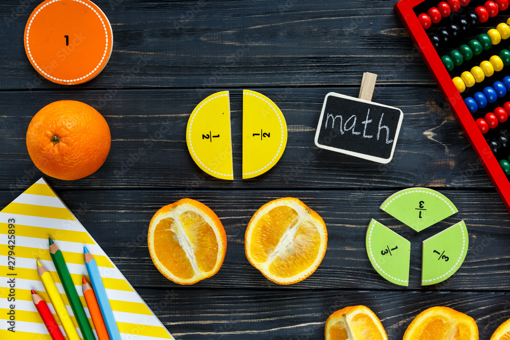 Сolorful math fractions and oranges as a sample on dark wooden ...