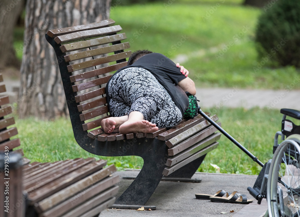 homeless disabled person sleeps on the bench Stock Photo | Adobe Stock