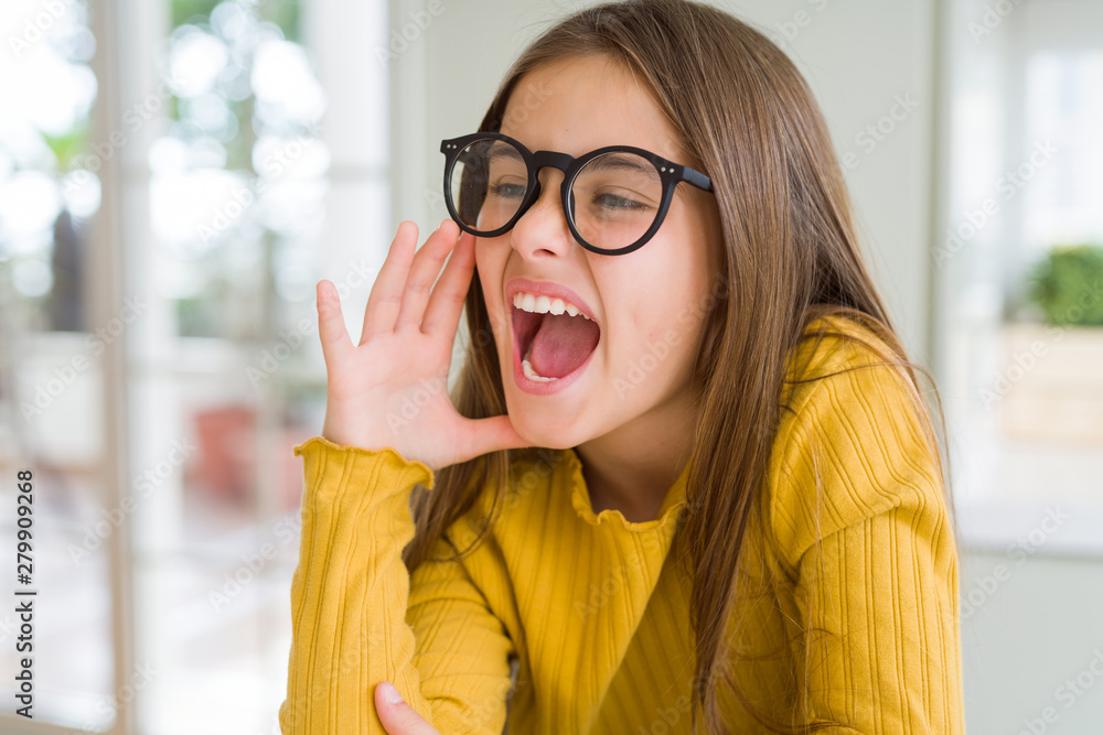 Beautiful young girl kid wearing glasses shouting and screaming loud to ...