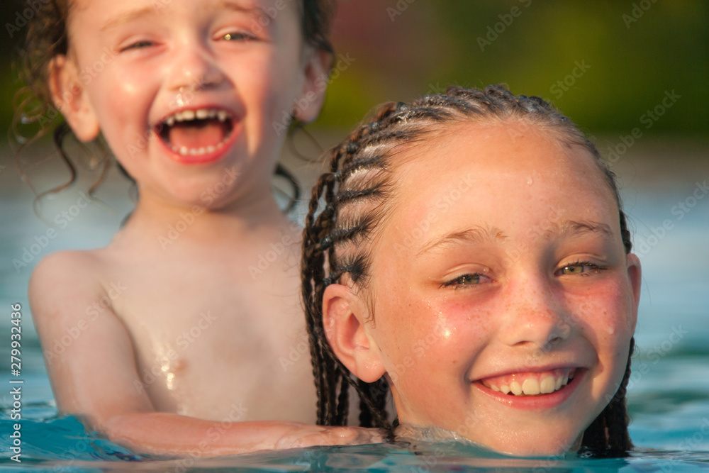 Little boy getting a piggyback ride from older girl while swimming in a ...