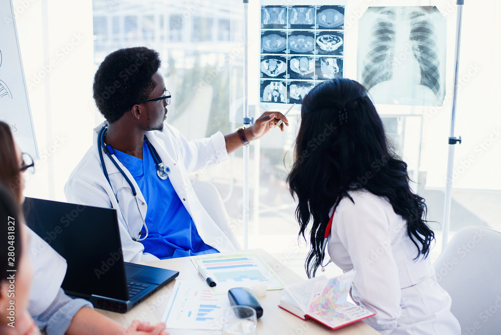 African doctor shows and explains MRI results to his professional team ...