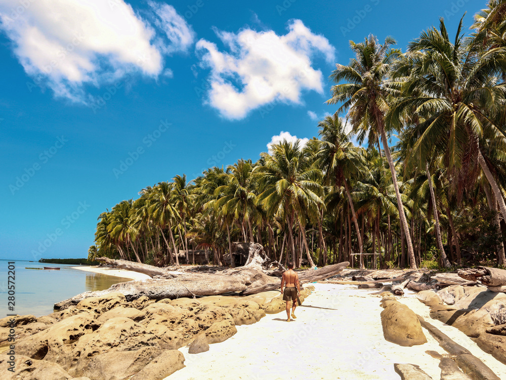 Man walking on the white beach and turquoise water with clear blue sky ...