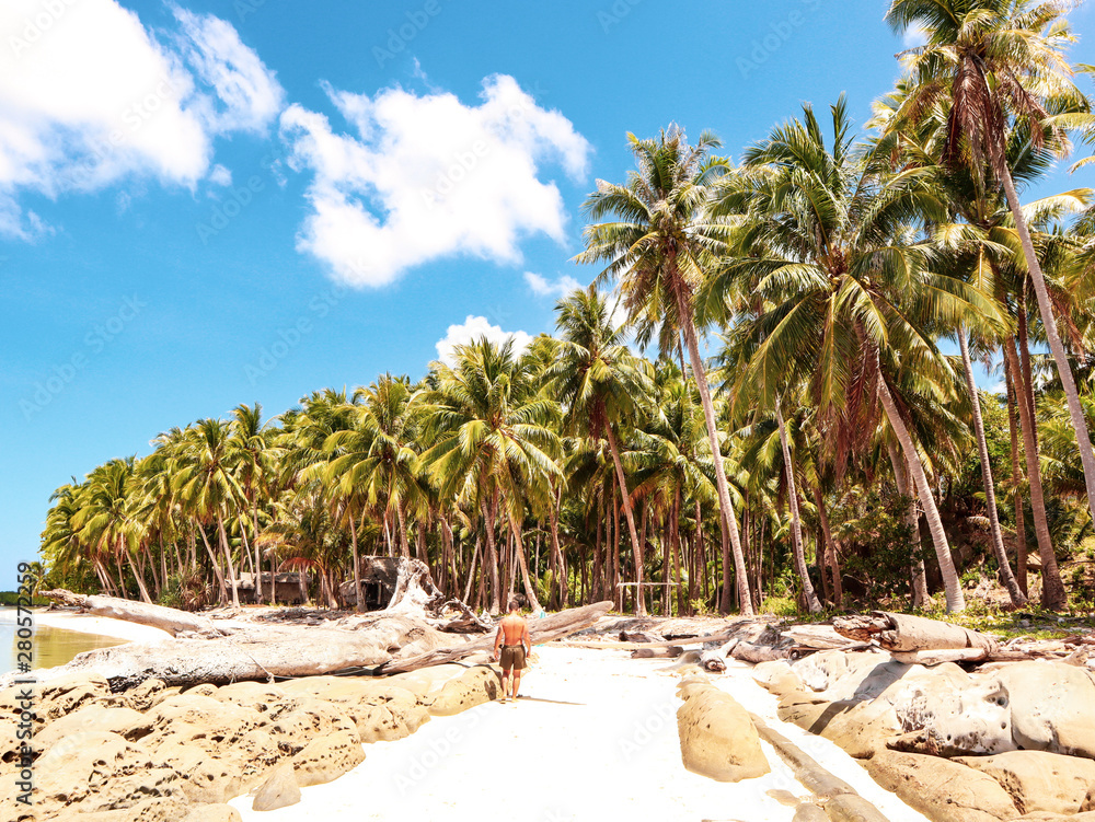 Man walking on the white beach and turquoise water with clear blue sky ...